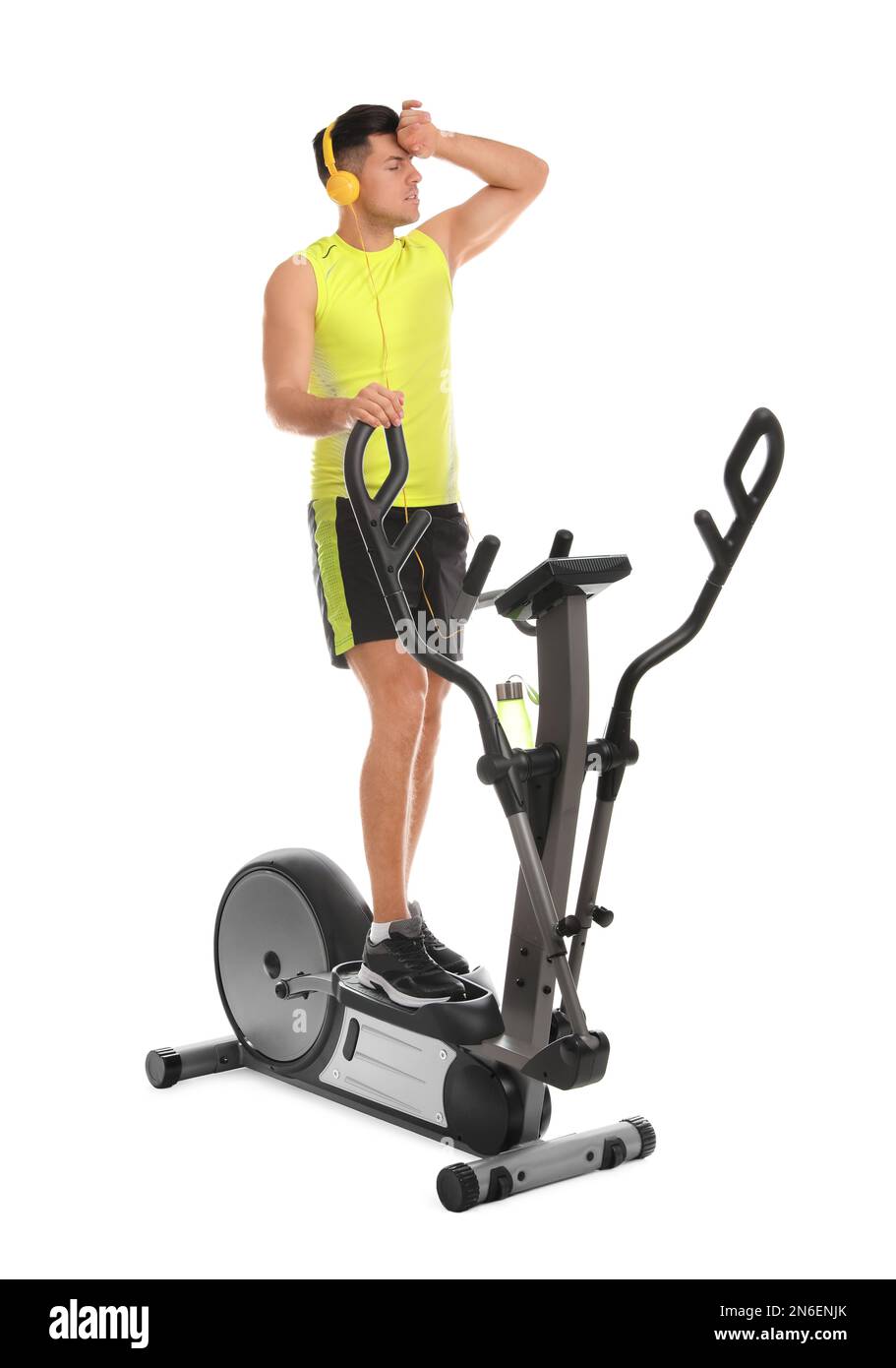 Tired man after training on modern elliptical machine against white ...