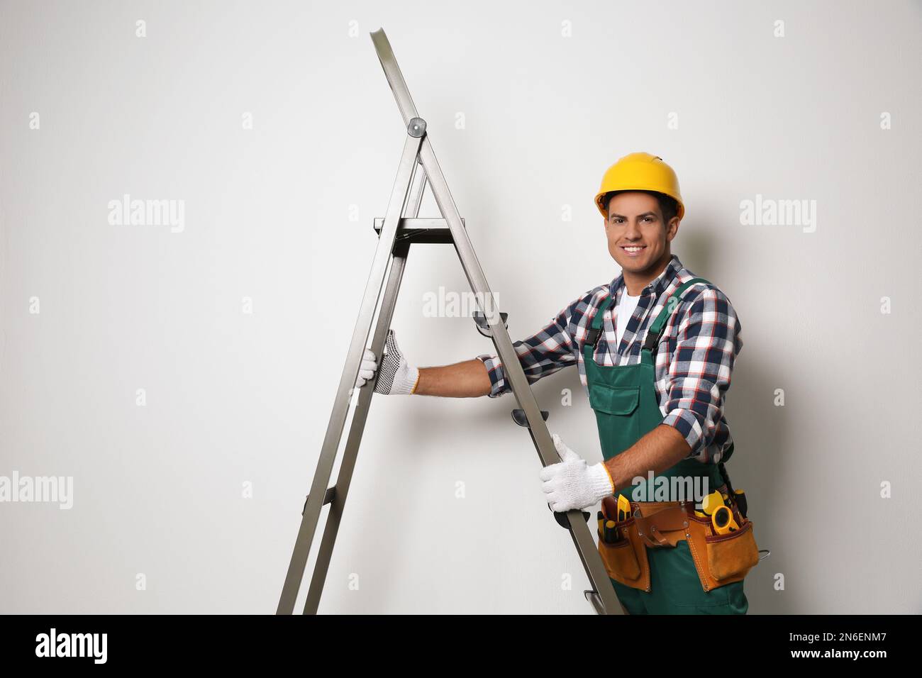 Professional builder with metal ladder on light background Stock Photo ...