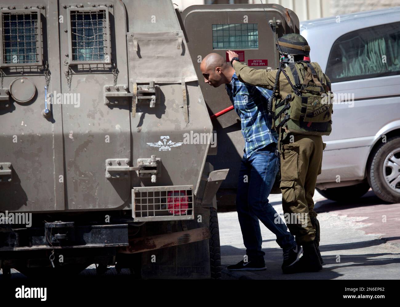 An Israeli soldier arrests a Palestinian man during an army operation ...
