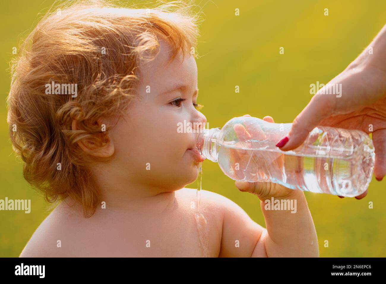 Baby kids drinking water from mother hands. Baby boy with curly blond ...