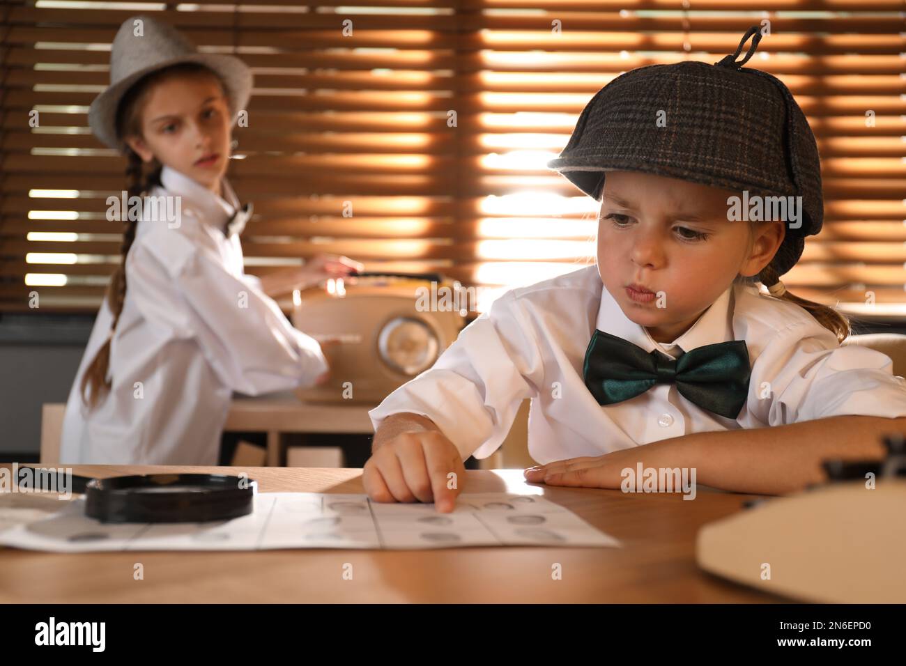 Cute little detective exploring fingerprints while her colleague ...