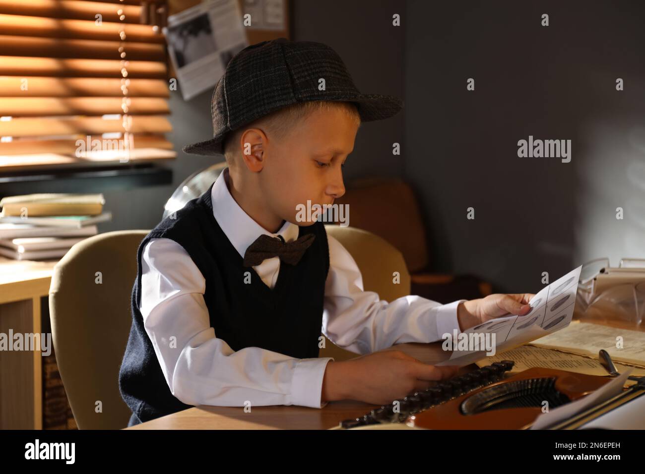 Cute little detective with fingerprints card at table in office Stock ...