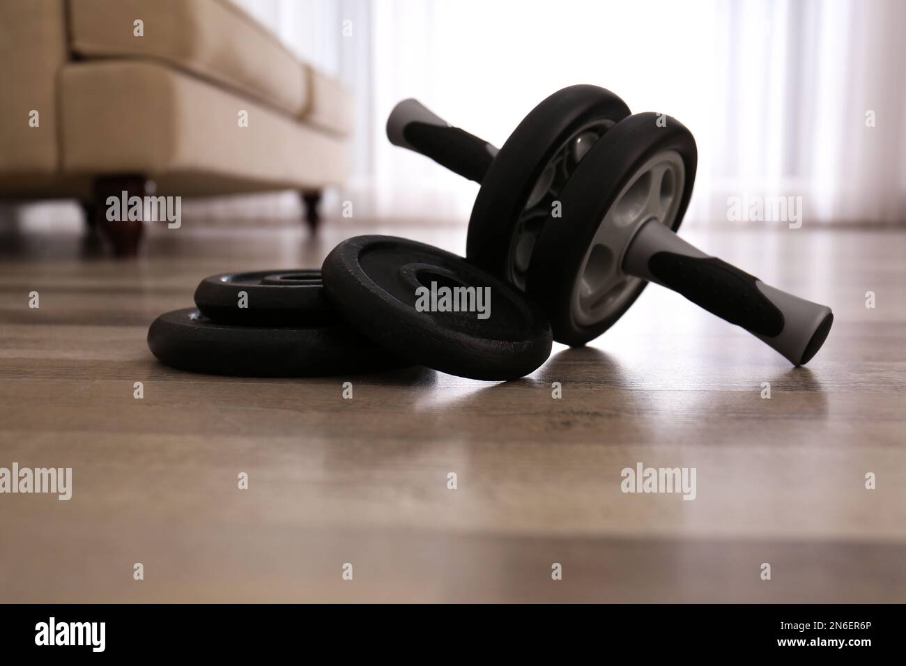 Abs roller and weight plates on floor in room. Home fitness Stock Photo ...