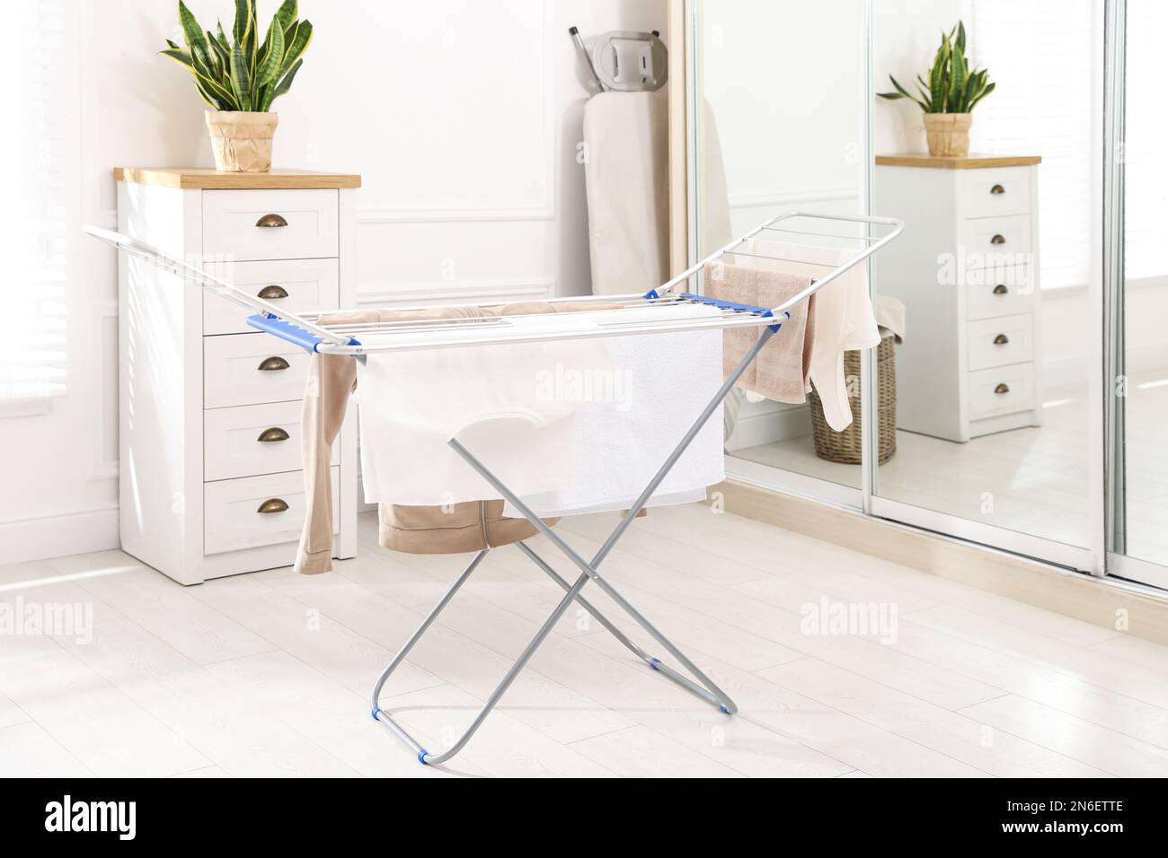 Clean laundry hanging on drying rack indoors Stock Photo - Alamy