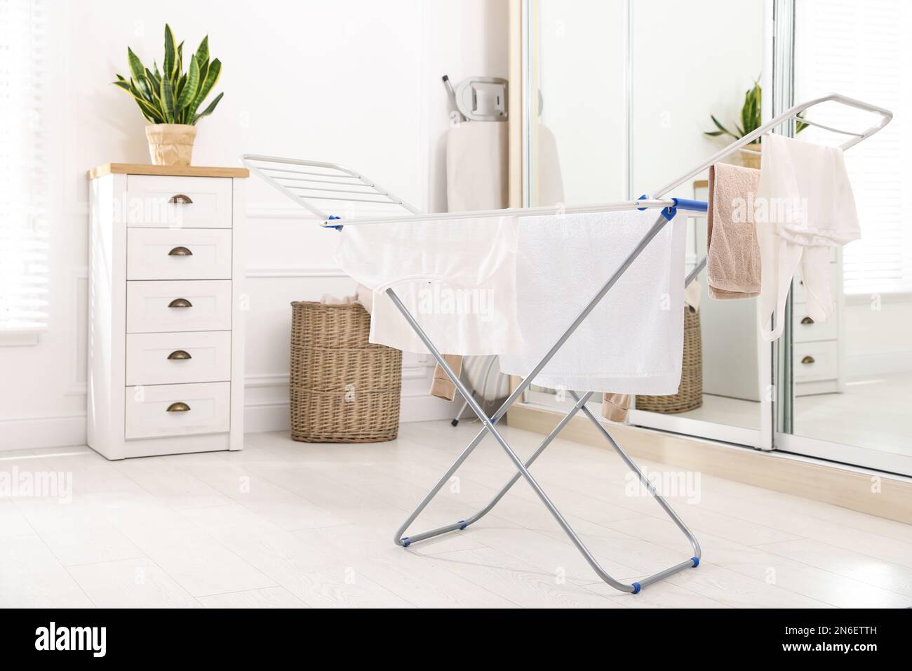 Clean laundry hanging on drying rack indoors Stock Photo - Alamy