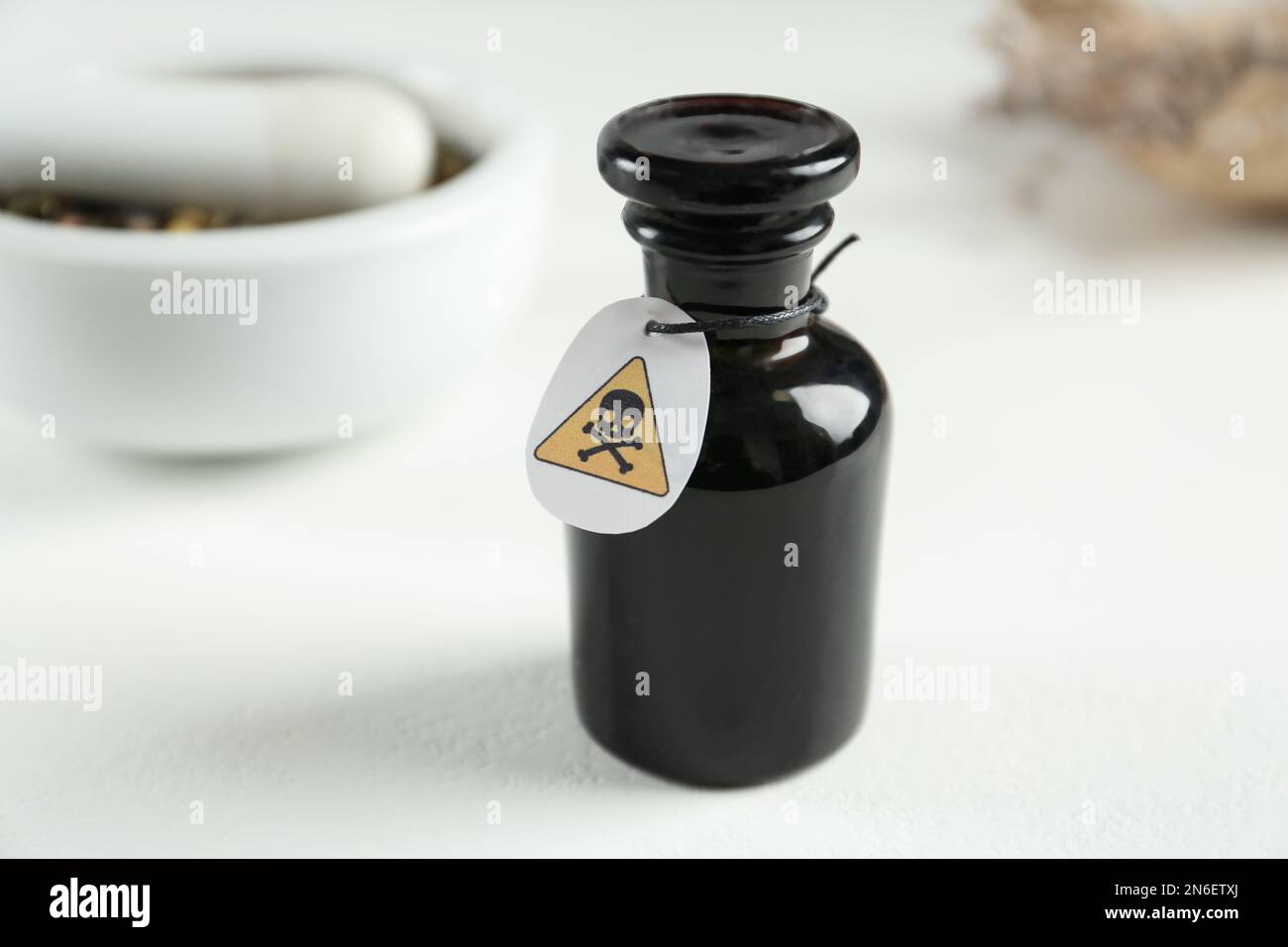 Glass bottle of poison with warning sign on light background, closeup ...
