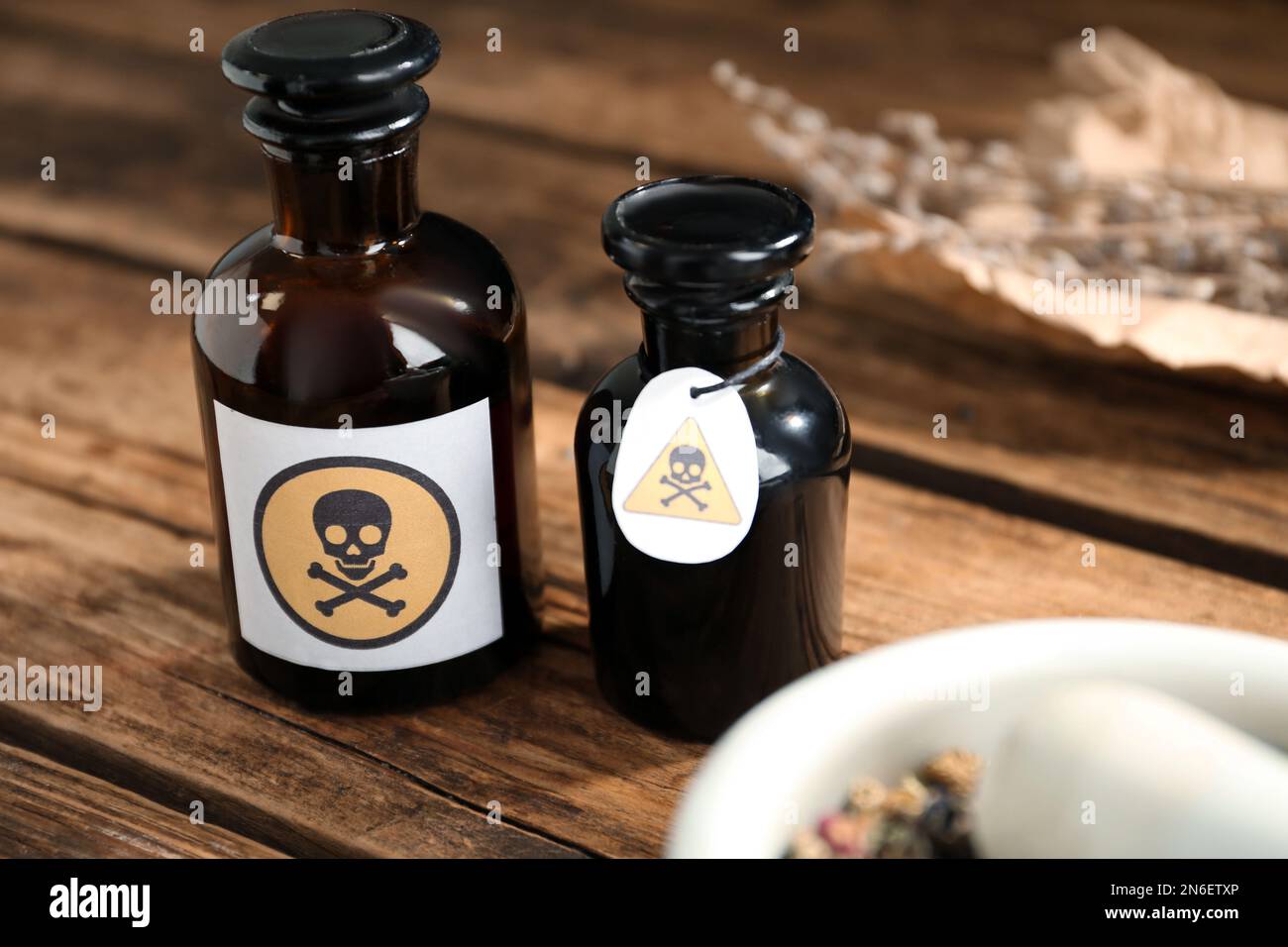 Glass bottles of poison with warning signs on wooden table Stock Photo ...