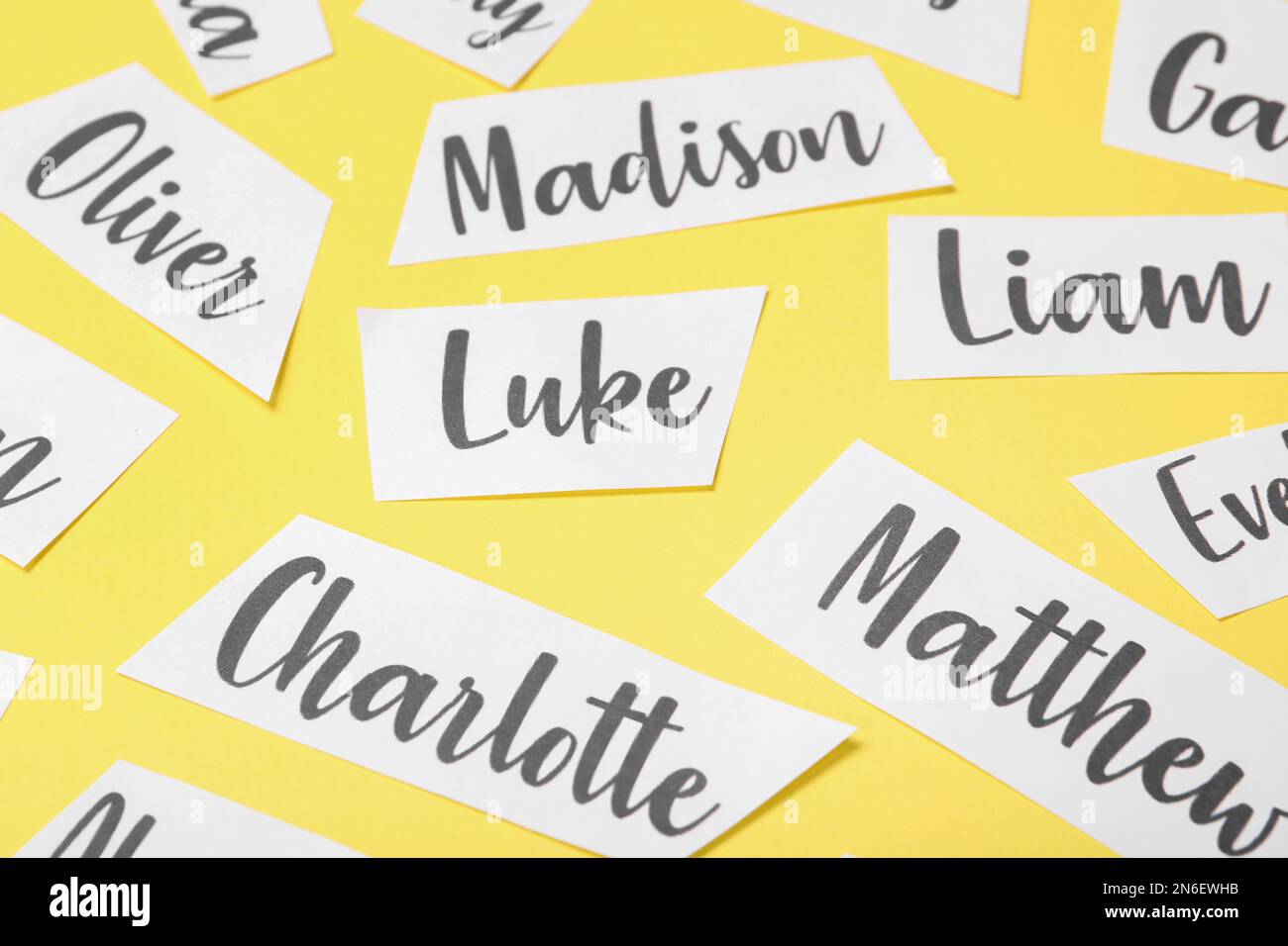 Paper sheets with written different baby names on yellow background ...