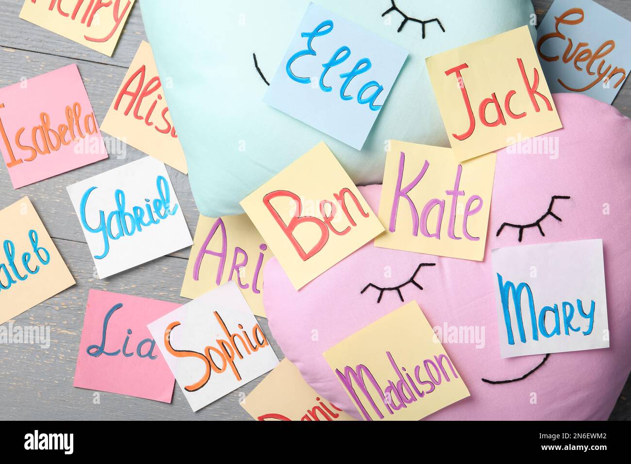 Colorful paper sheets with written different baby names on grey wooden ...