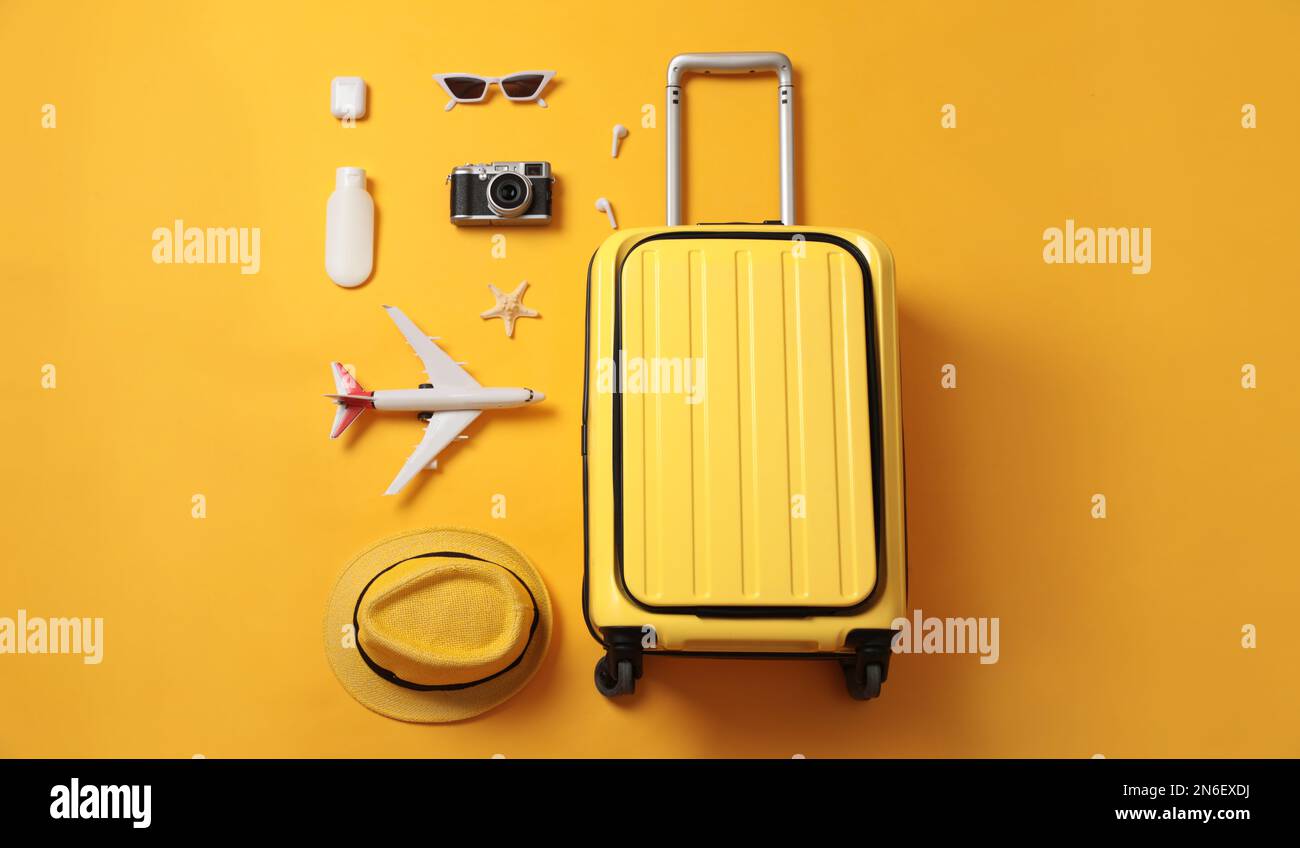 Flat lay composition with suitcase and travel accessories on yellow ...