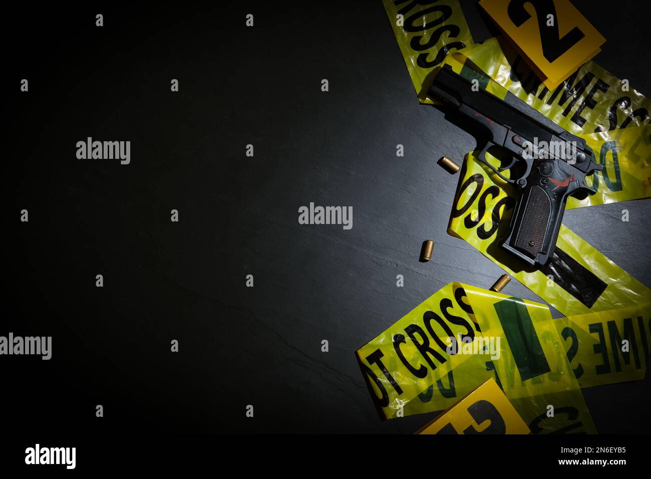 Flat lay composition with gun and crime scene tape on black slate ...
