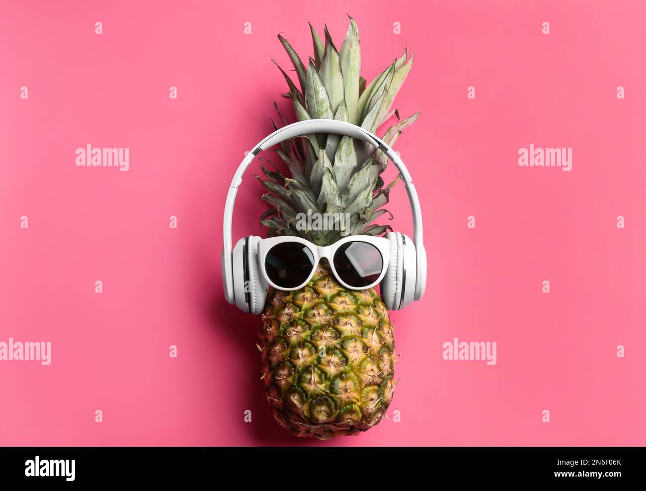 Pineapple with sunglasses and headphones on pink background, top view ...