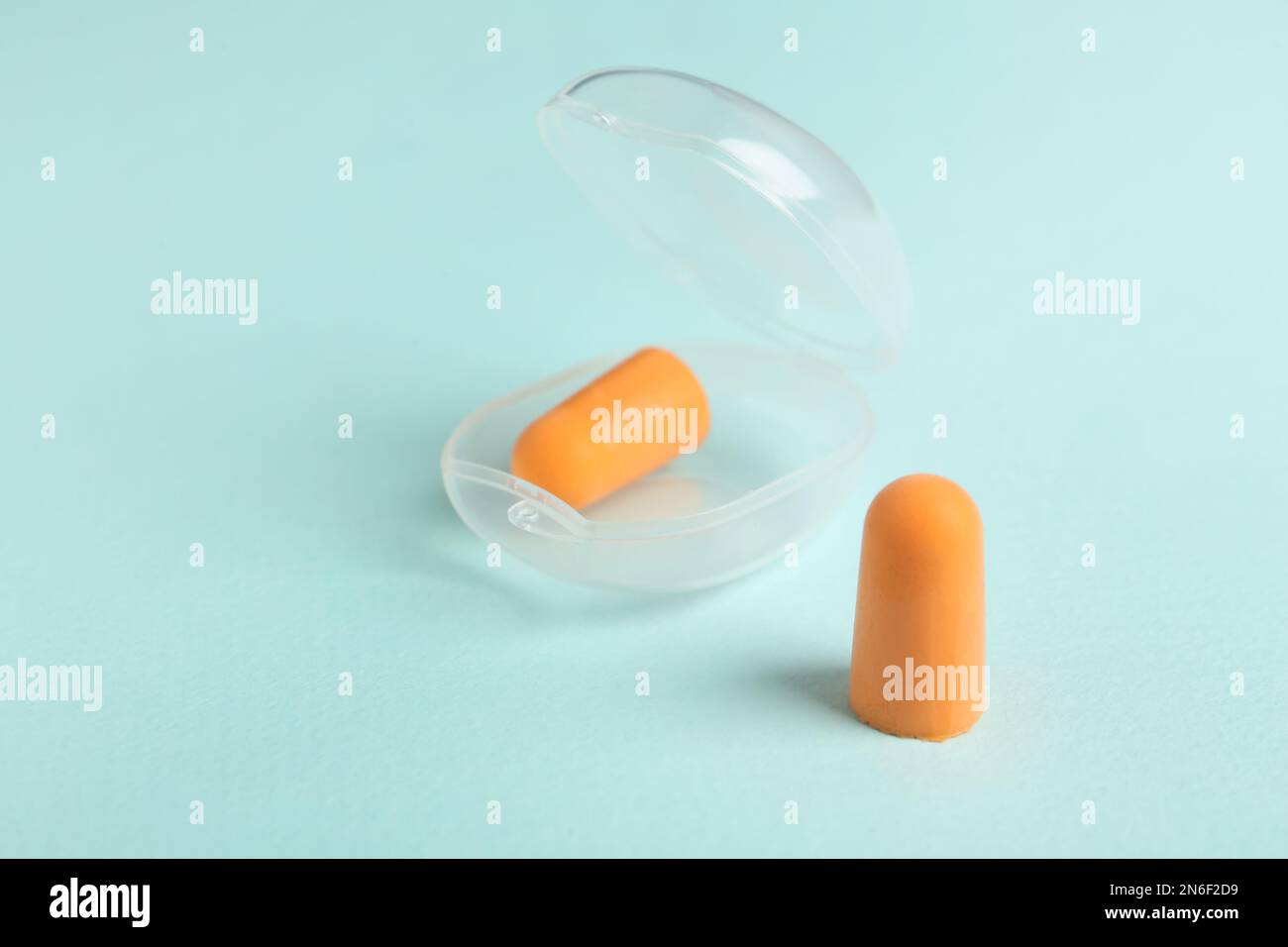 Pair of orange ear plugs and case on turquoise background Stock Photo ...