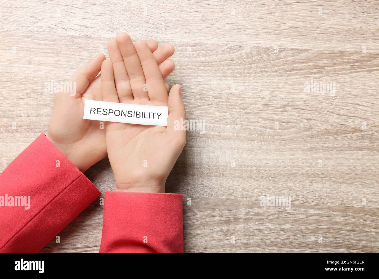 Woman holding card with word Responsibility at wooden table, top view ...