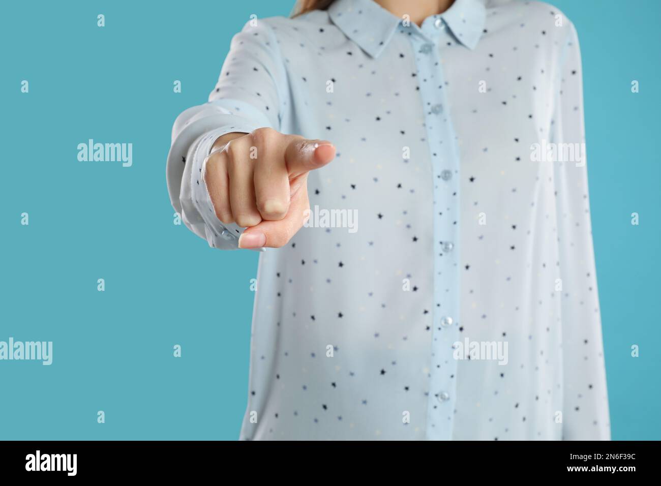 Woman pointing at something on light blue background, closeup. Finger ...