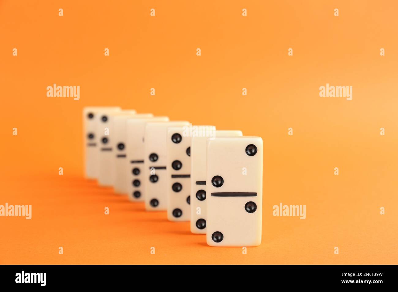 White domino tiles with black pips on orange background Stock Photo - Alamy