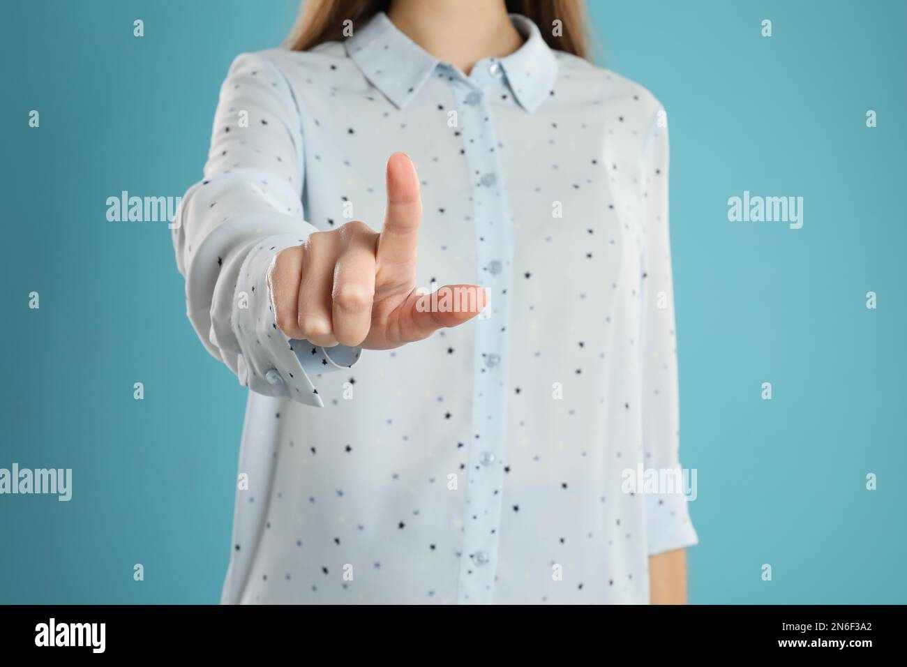 Woman pointing at something on light blue background, closeup. Finger ...