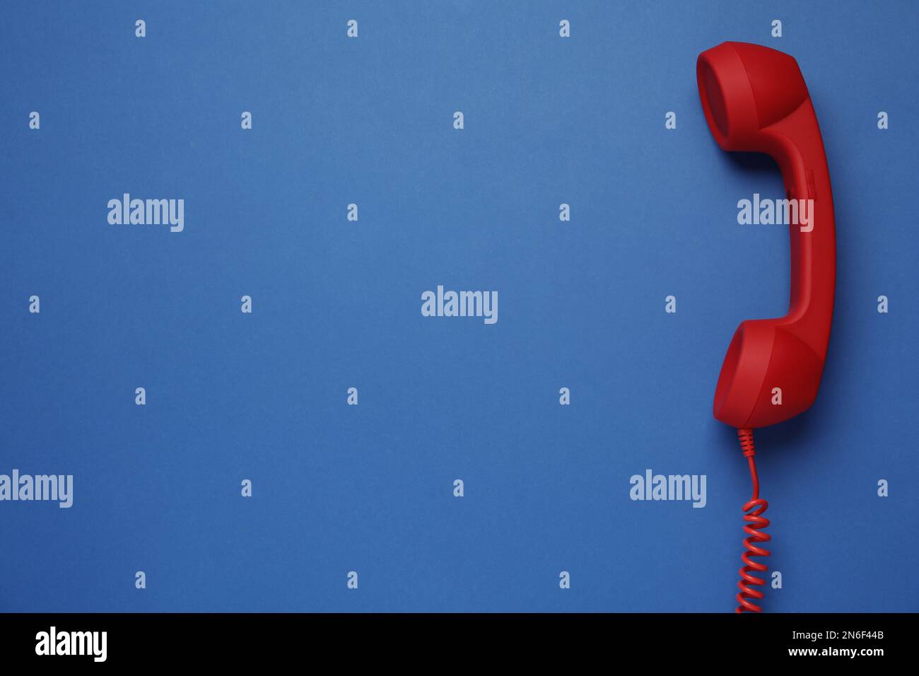 Red corded telephone handset on blue background, top view. Hotline ...
