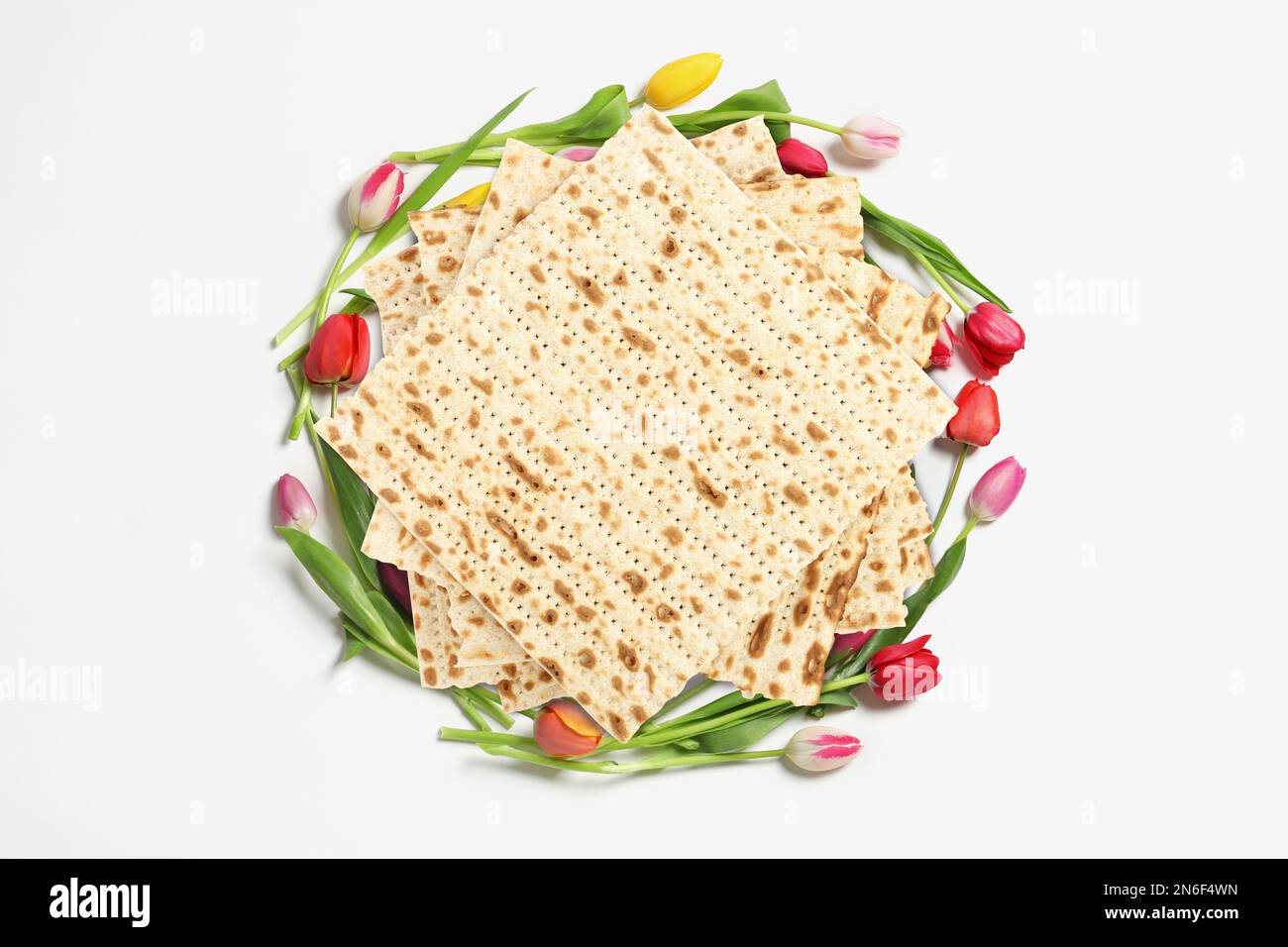 Tasty matzos and flowers on white background, top view. Passover ...