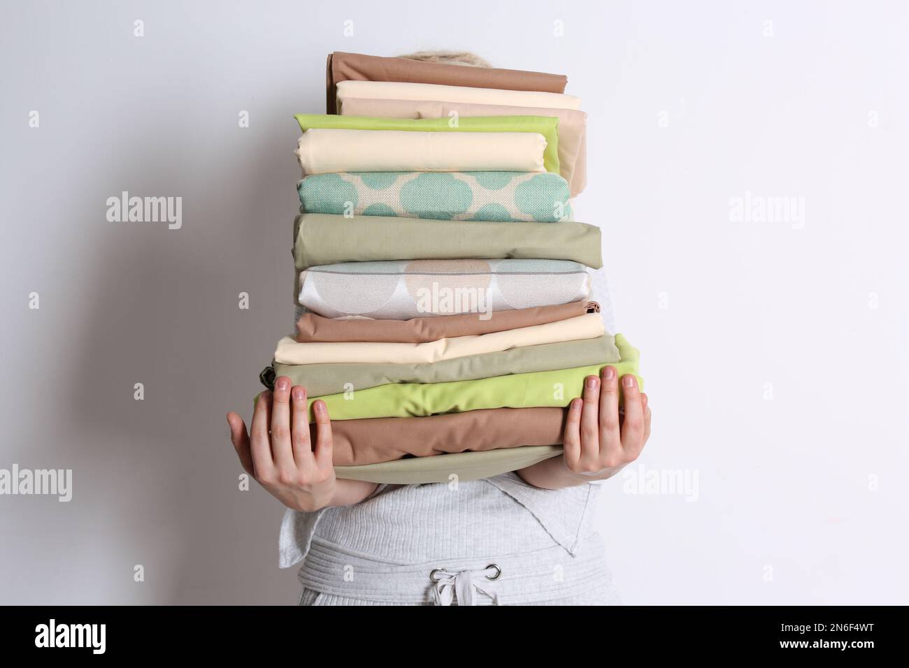 Woman holding stack of clean bed linens on white background Stock Photo ...