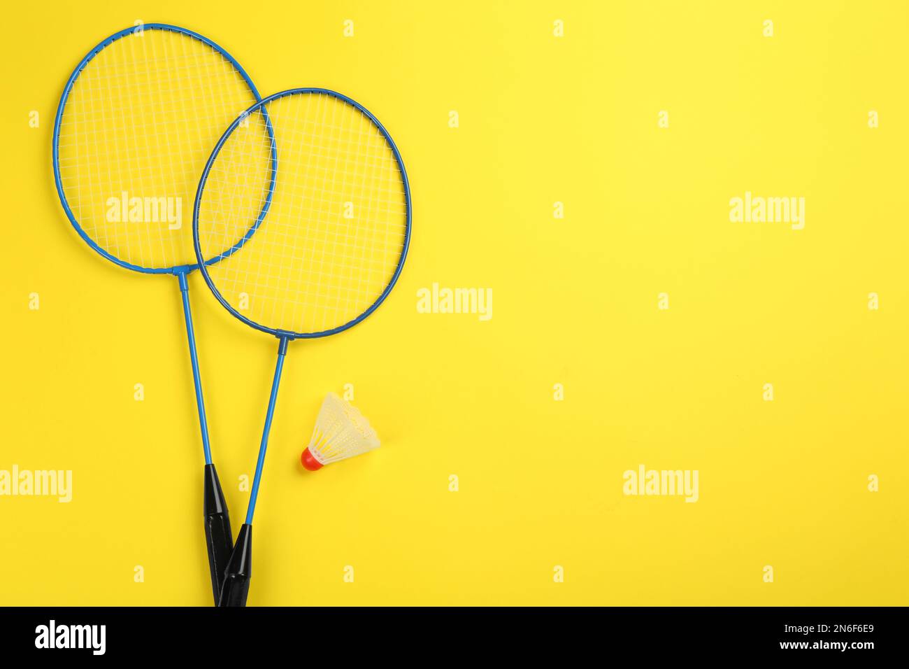 Rackets and shuttlecock on yellow background, flat lay with space for ...
