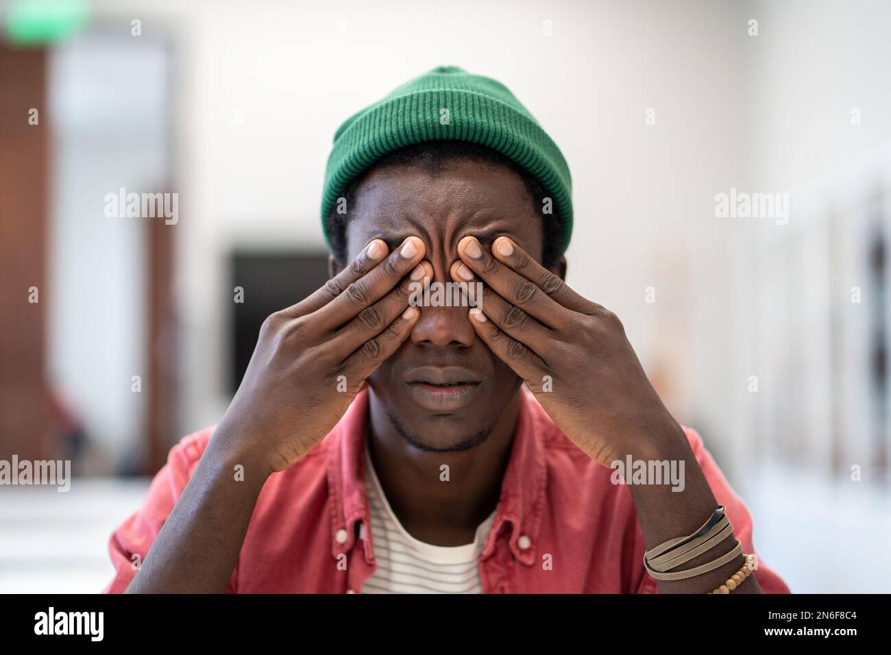 Tired stressed African guy student sitting in library massaging eyes ...