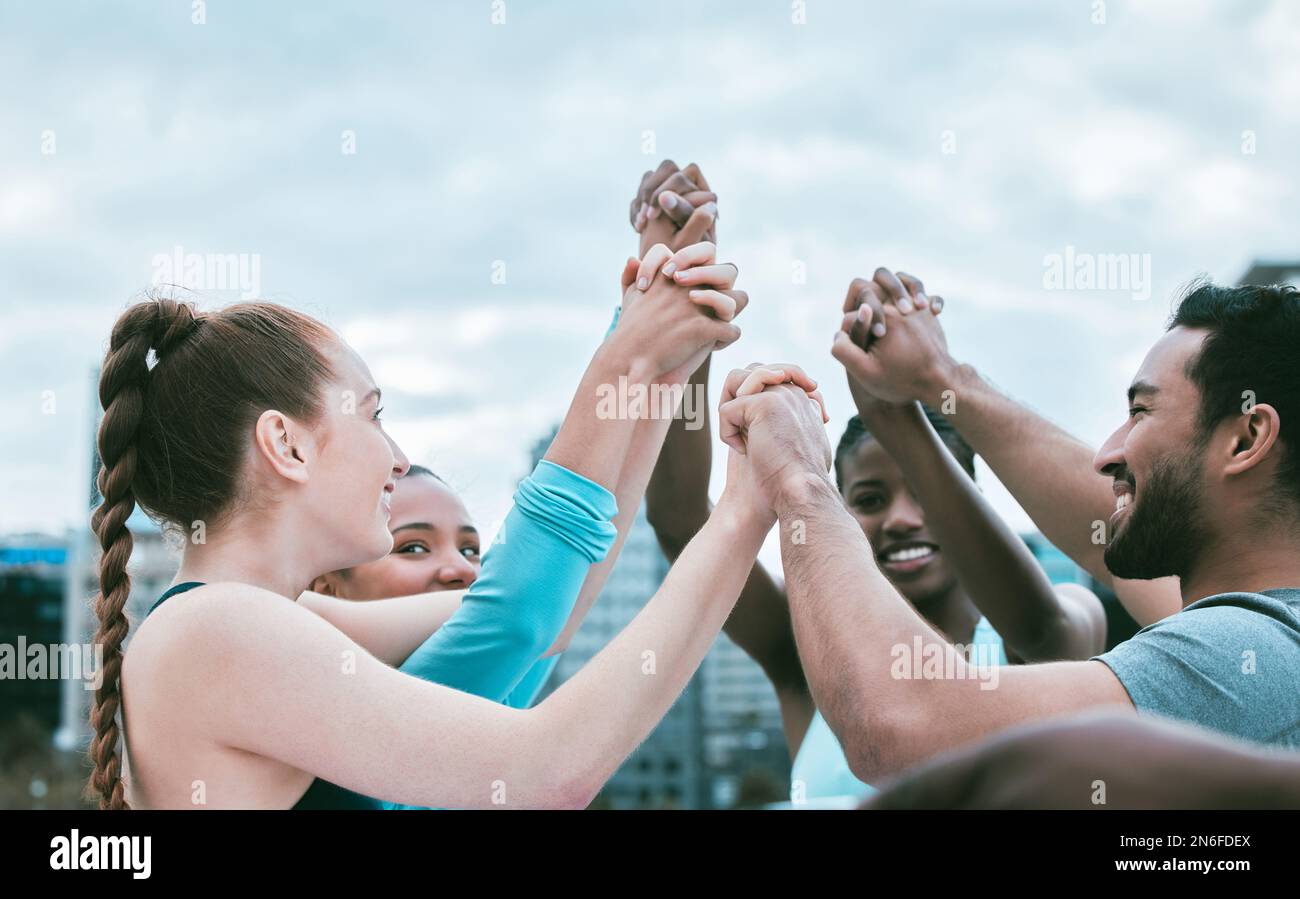 Diverse group of people holding hands with arms raised to express unity ...