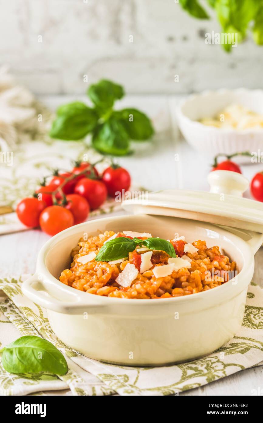 Homemade tomato risotto with fresh basil on a white wooden table ...