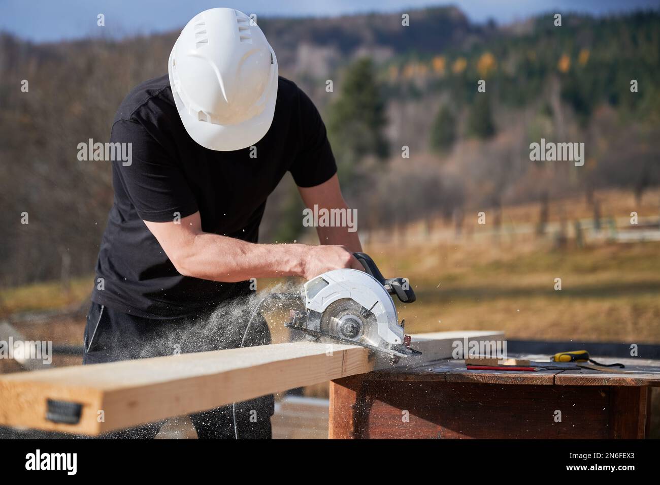 Carpenter using circular saw for cutting wood beam. Man worker building ...