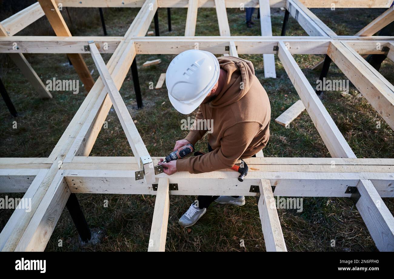 Man worker building wooden frame house on pile foundation. Carpenter ...