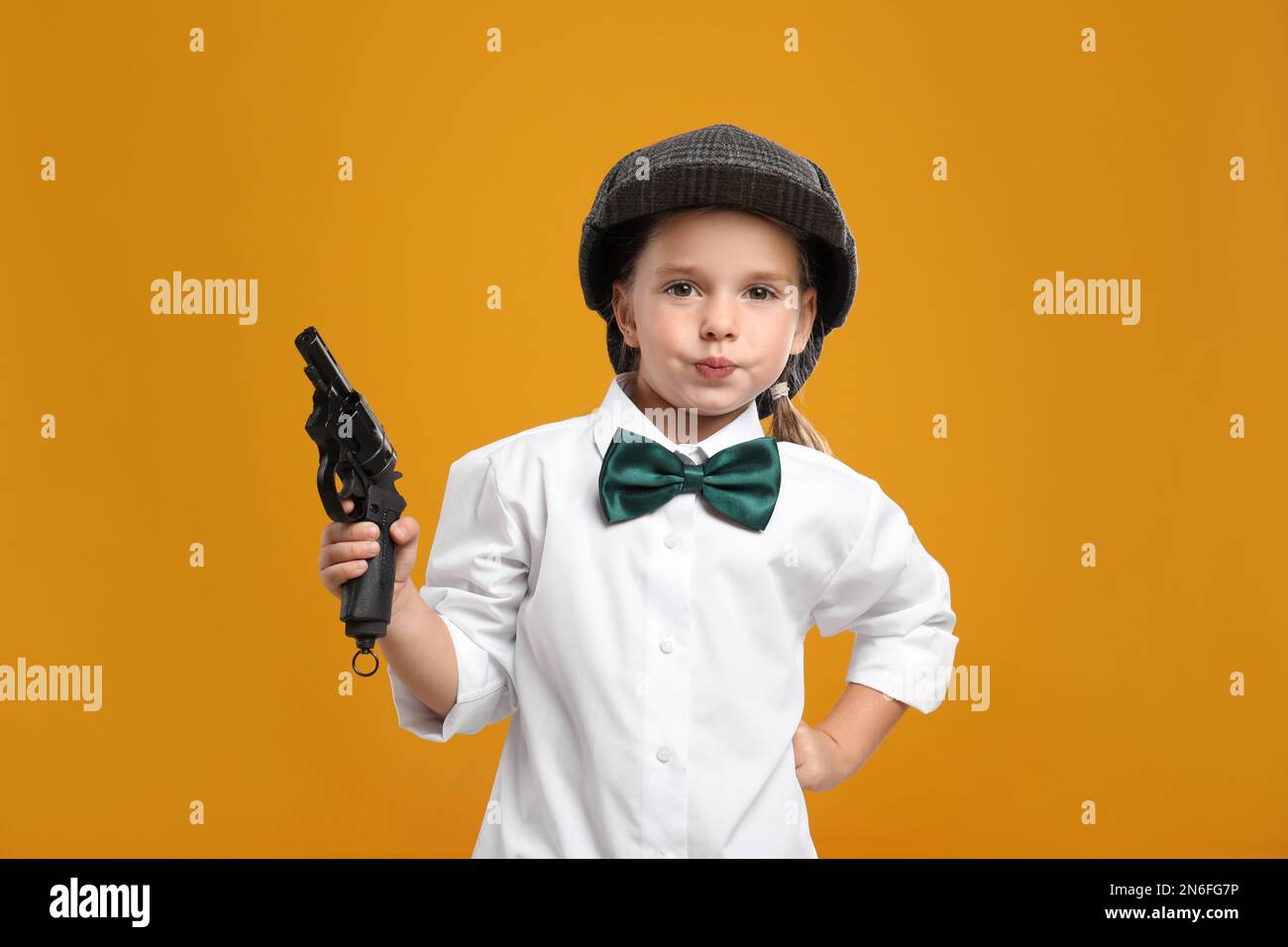 Cute little detective with revolver on yellow background Stock Photo ...