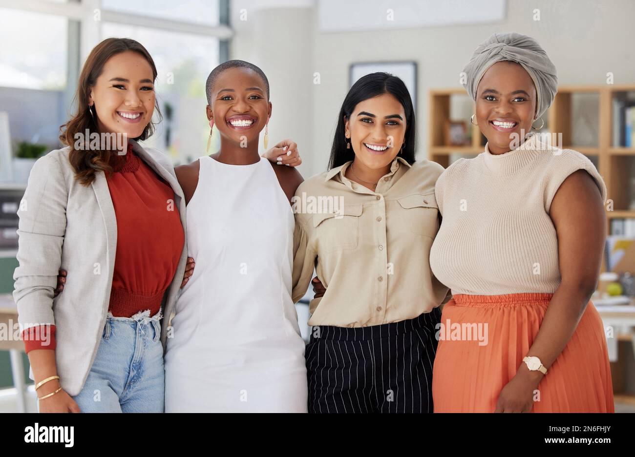 Portrait of a diverse group of smiling ethnic business women standing together in the office ...