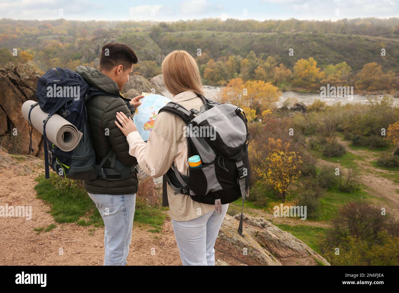 Couple of travelers with backpacks and map planning trip in mountains ...