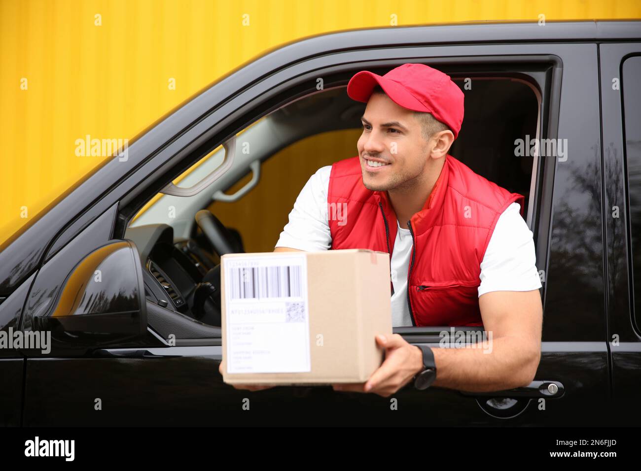 Courier giving parcel out of car window outdoors Stock Photo - Alamy