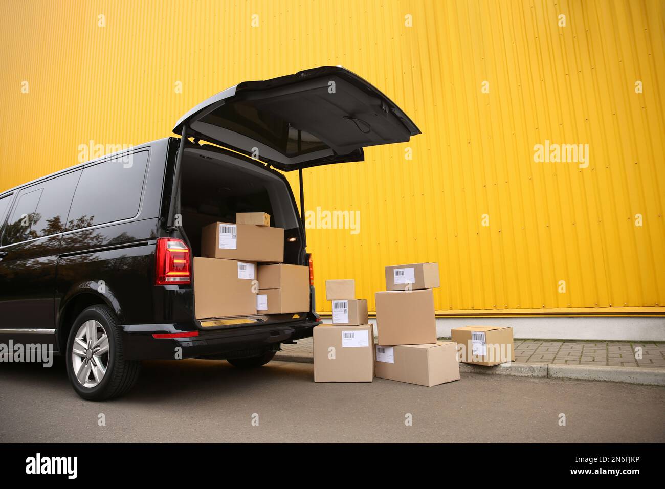Black delivery van and many different parcels near yellow building ...