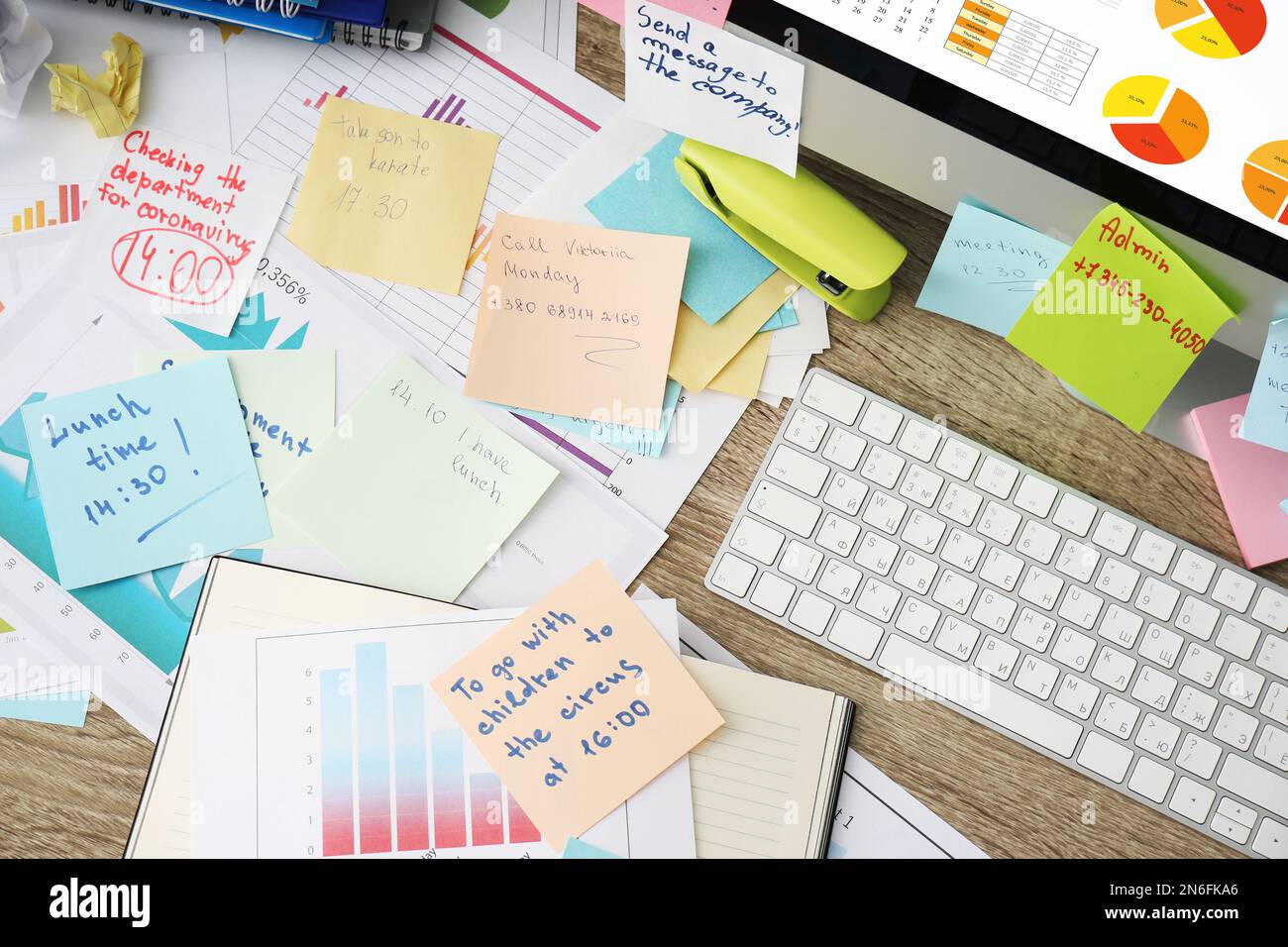 Computer, notes and office stationery in mess on desk, top view ...