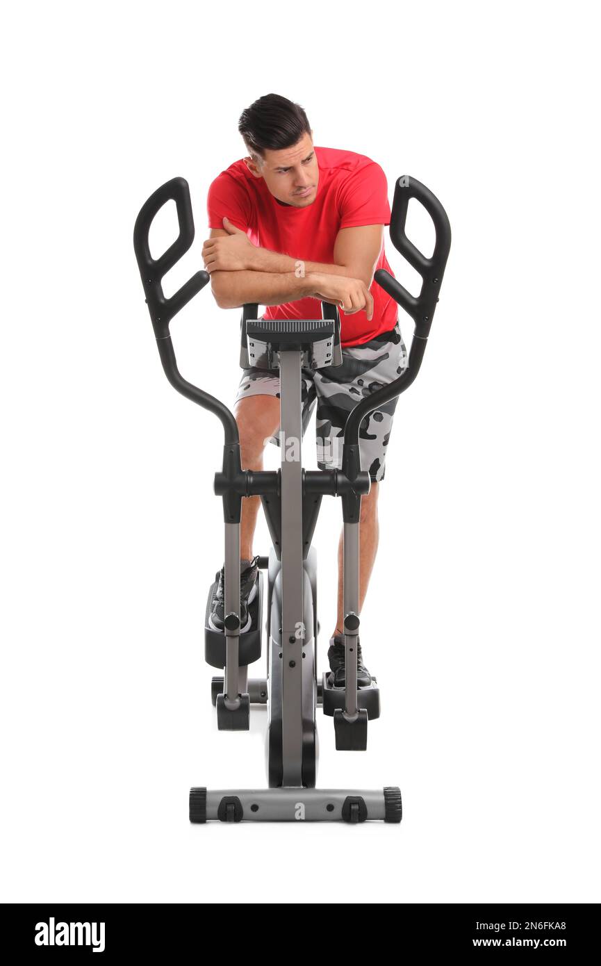 Tired man after training on modern elliptical machine against white ...