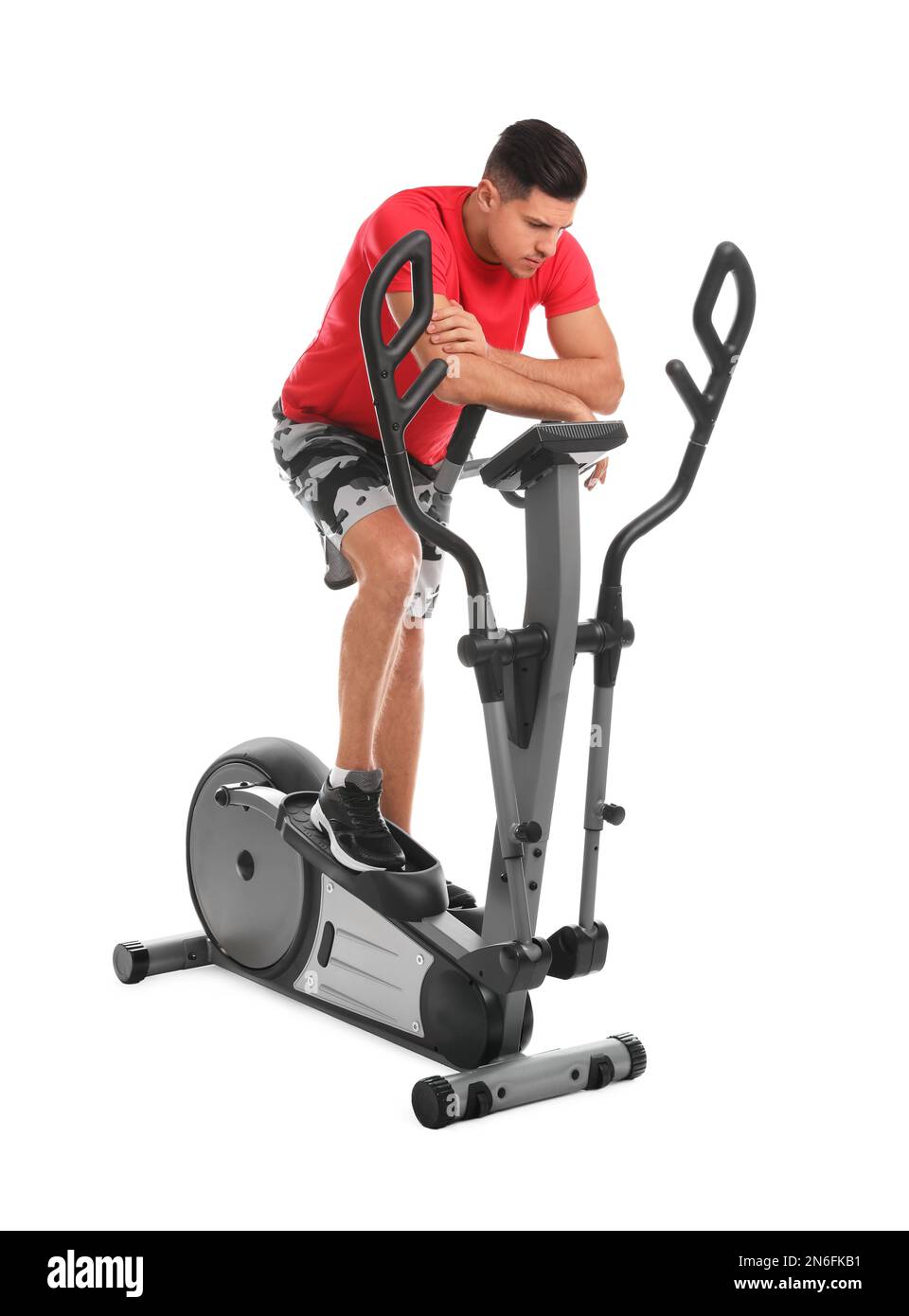 Tired man after training on modern elliptical machine against white ...
