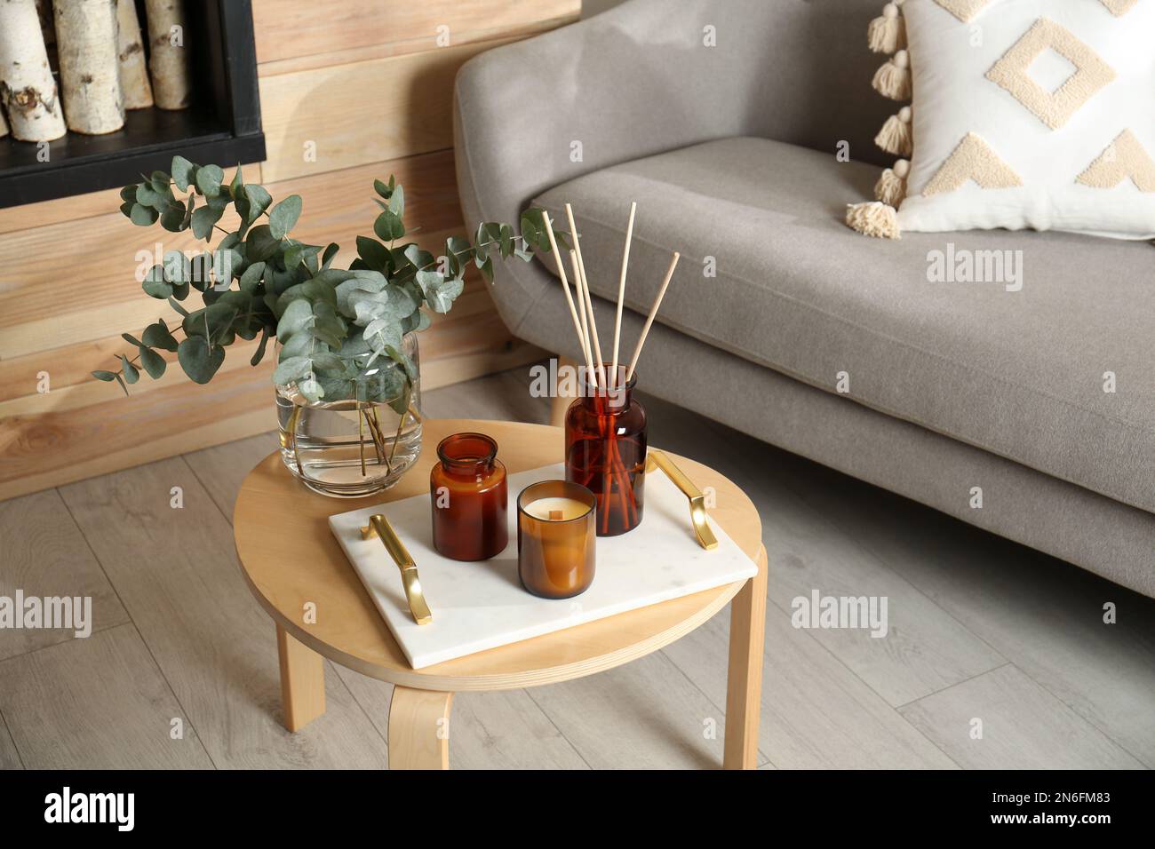 Eucalyptus branches, aromatic reed air freshener and candles on wooden ...