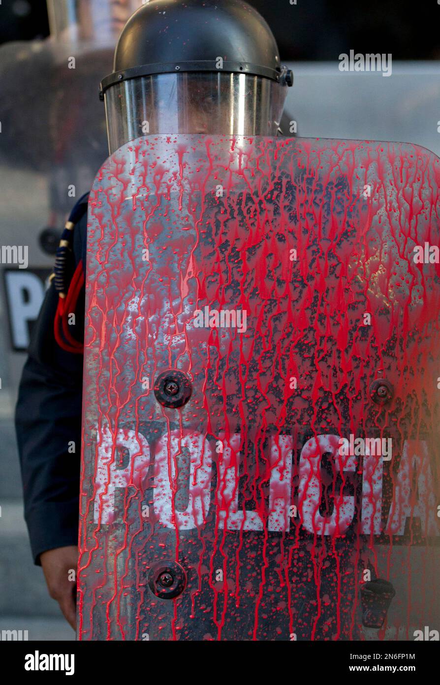 A police officer's shield is covered in red paint that was thrown by ...