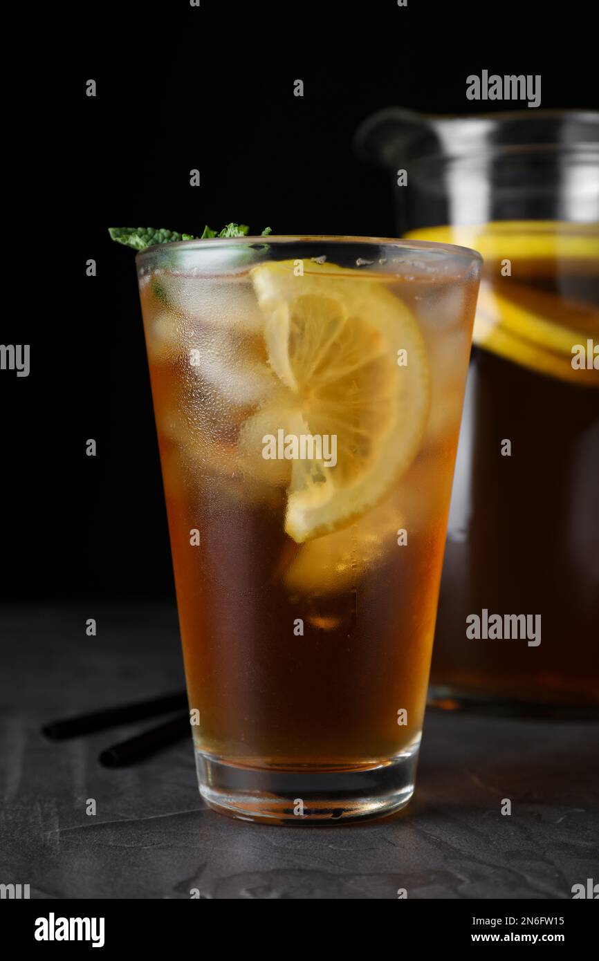 Delicious iced tea on grey table against black background, closeup ...