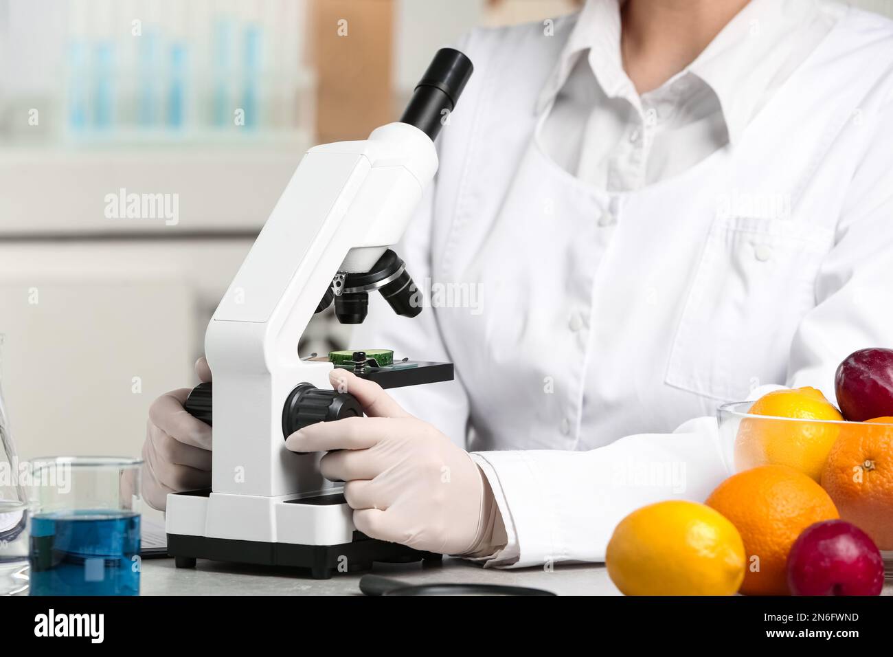 Scientist Inspecting Slice Of Cucumber With Microscope In Laboratory