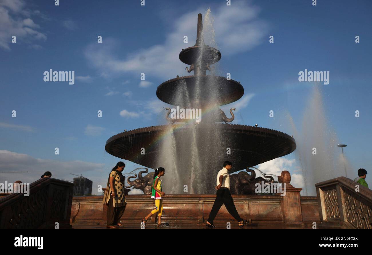 An Indian family walks near a fountain at Ambedkar Park, dedicated to ...