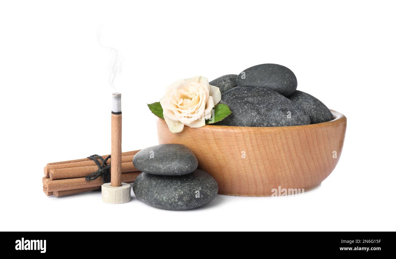 Composition with smoldering incense stick, rose and spa stones on white ...