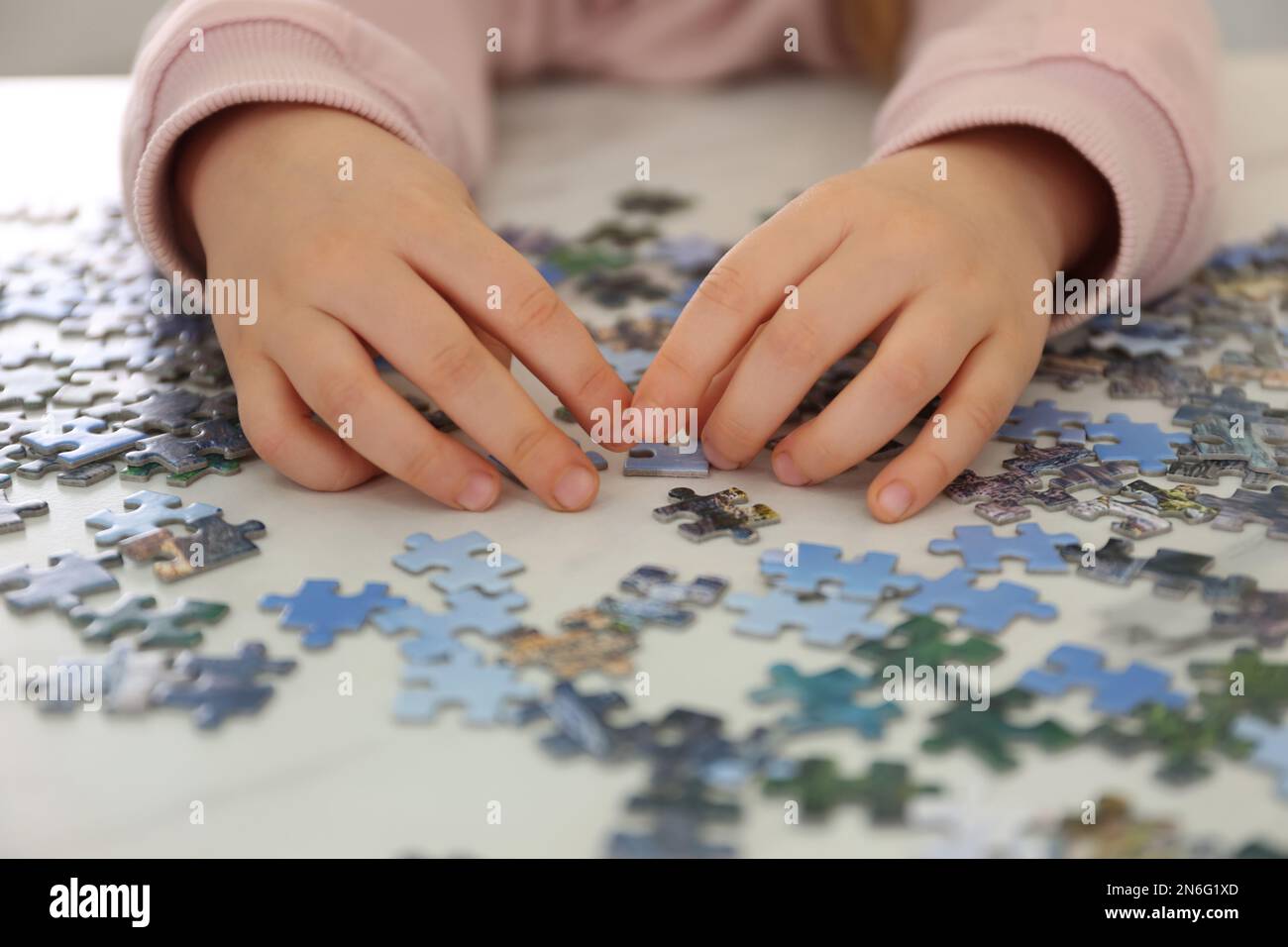 Little child playing with puzzles at table, closeup Stock Photo - Alamy