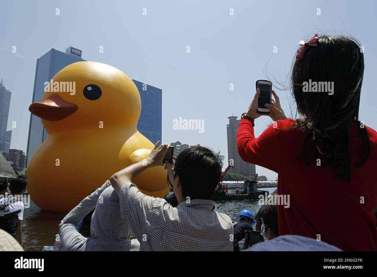 Spectators take photographs of the giant rubber duck in the port of ...