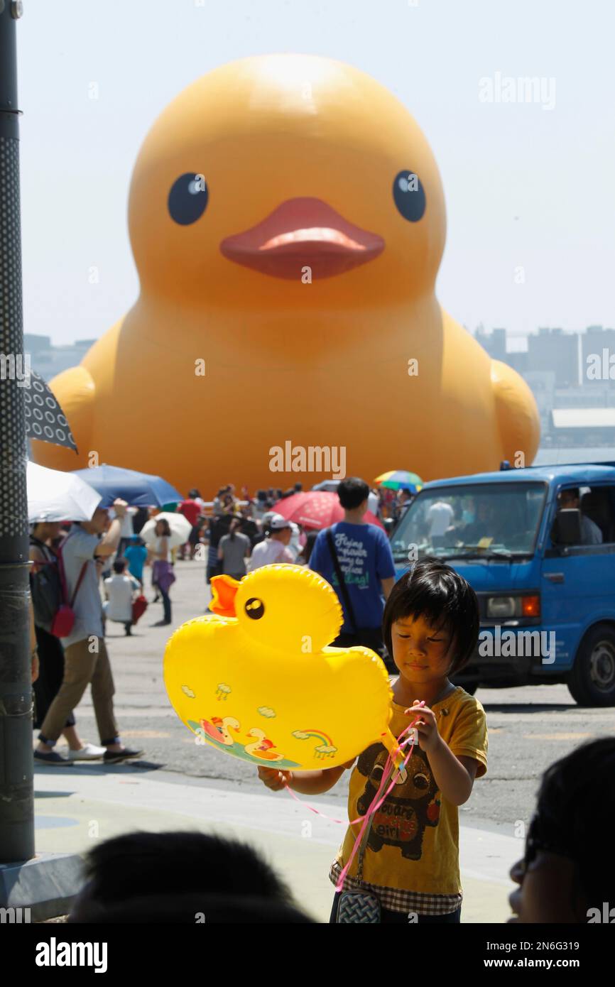 A young girl holds her duck balloon during the arrival of a giant ...