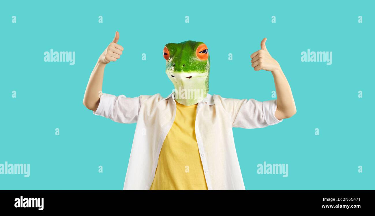 Funny humorous woman in rubber mask of frog's head shows thumbs up on ...