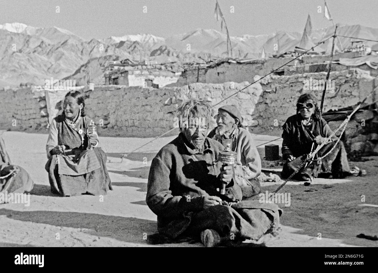 Tibetan refugees turning prayer wheels in front of Himalayan panorama ...