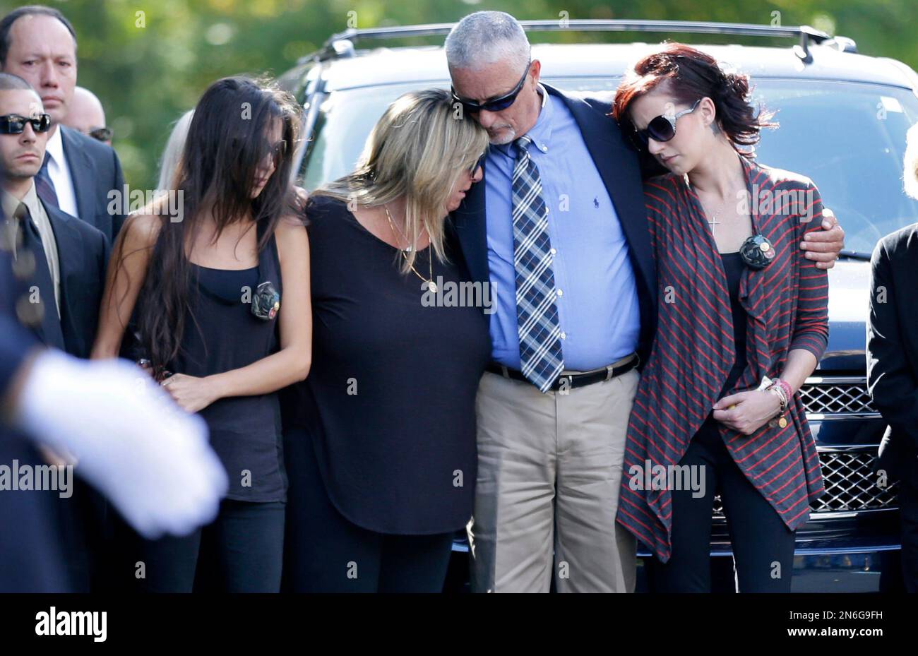 Raymond McGill, second from right, hugs his wife, Carol, center left ...